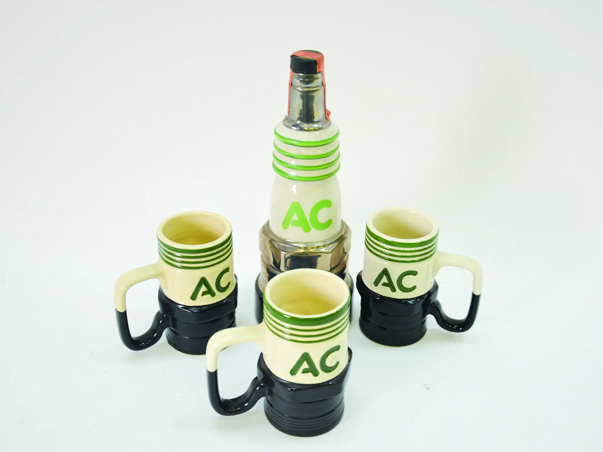 An AC spark plug ceramics grouping lot features three mugs and a spark ...